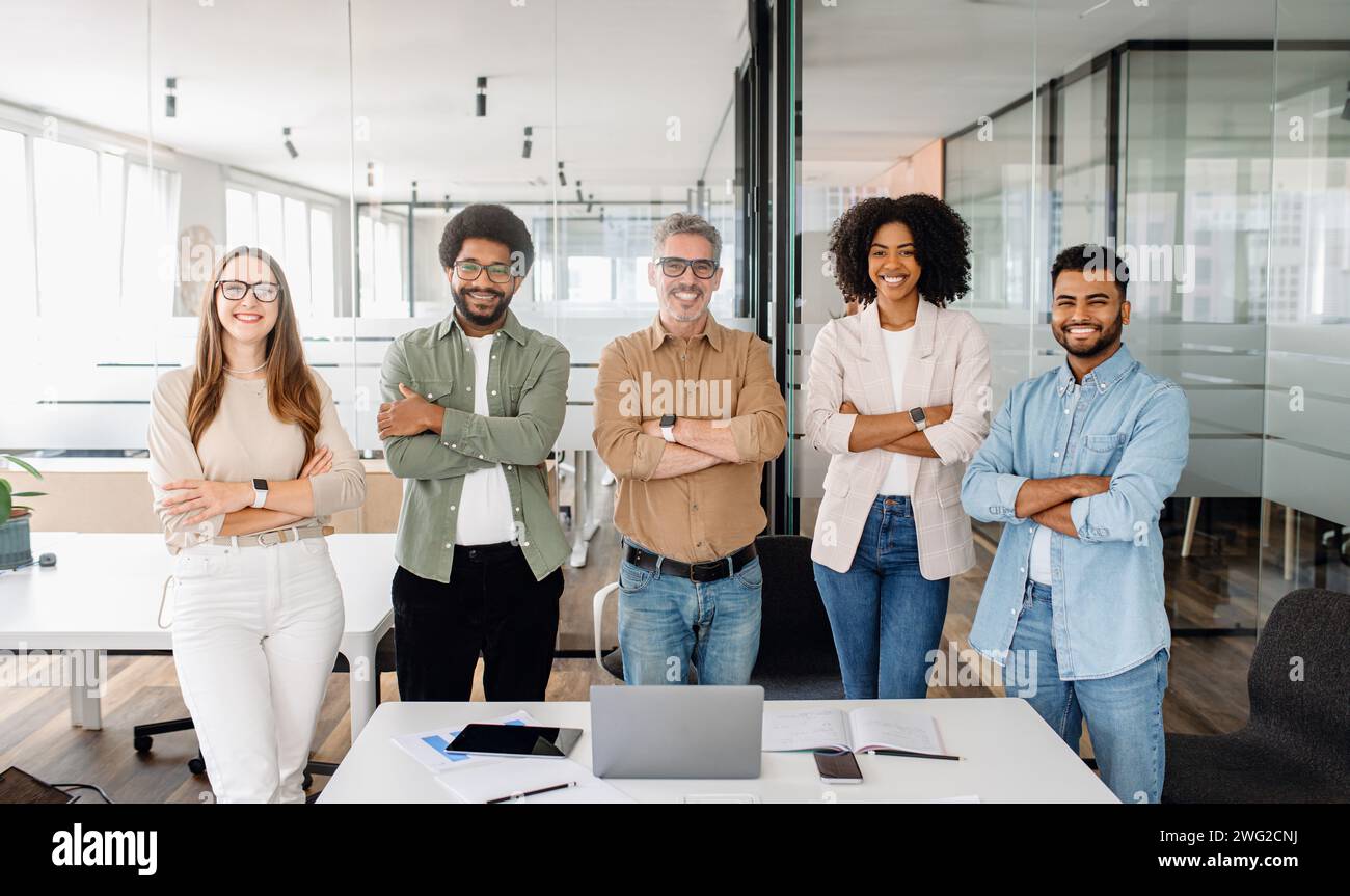 A diverse group of five colleagues stands confidently in the office ...