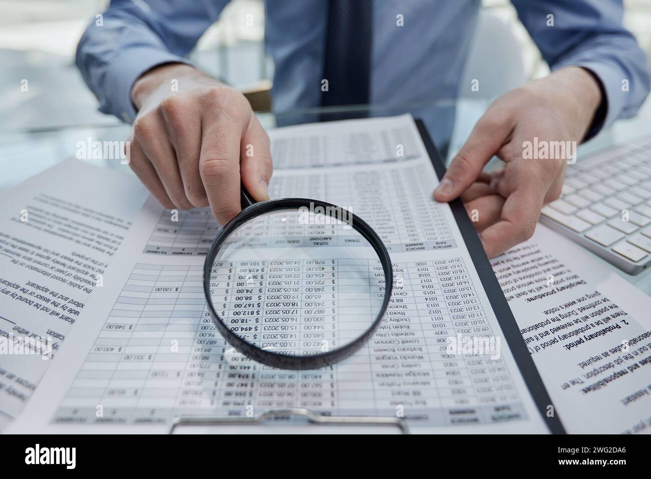 Businessman looking through a magnifying glass to documents Stock Photo ...