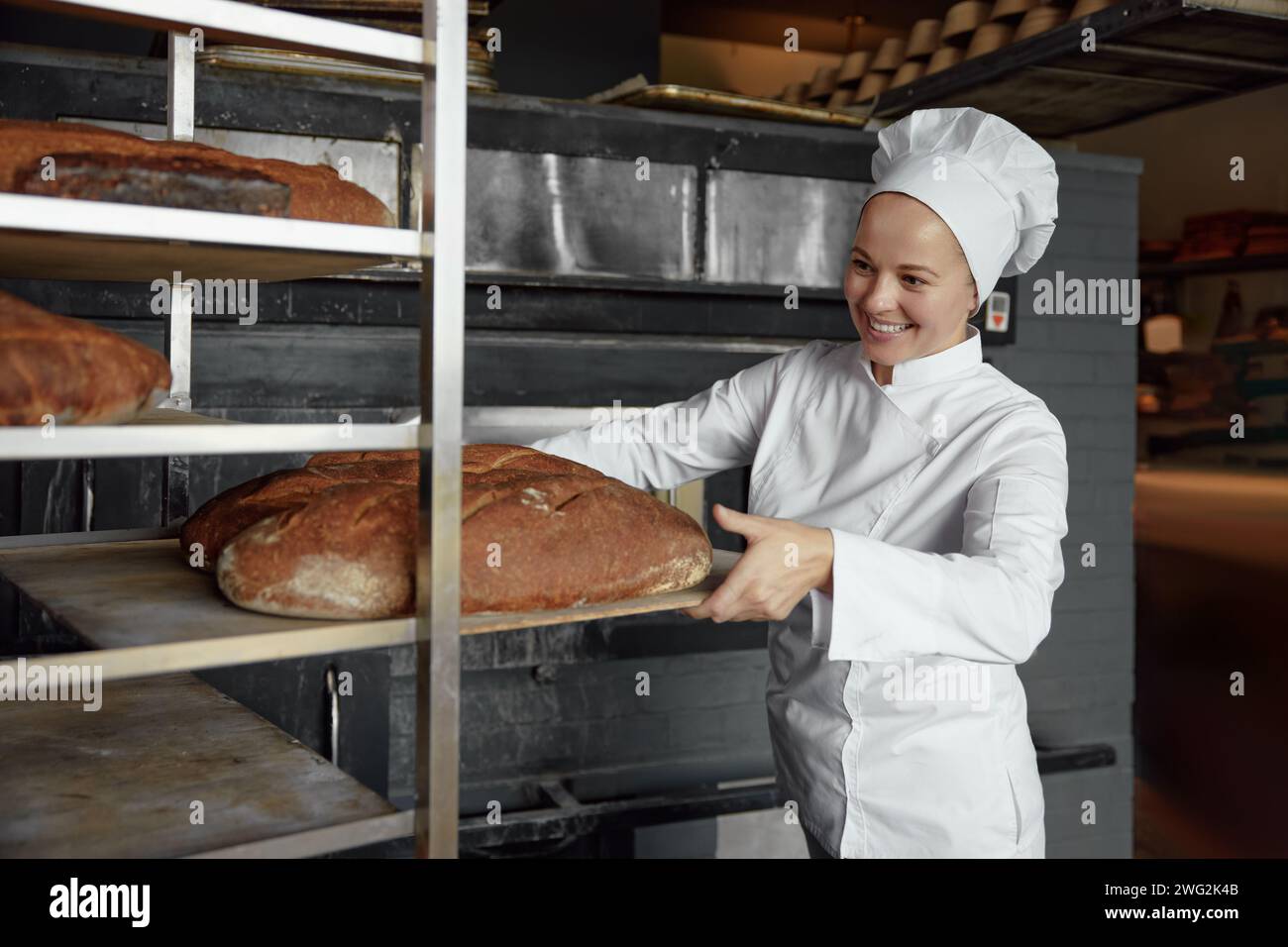Baker smiling happily pushing rack with fresh baked bread Stock Photo ...
