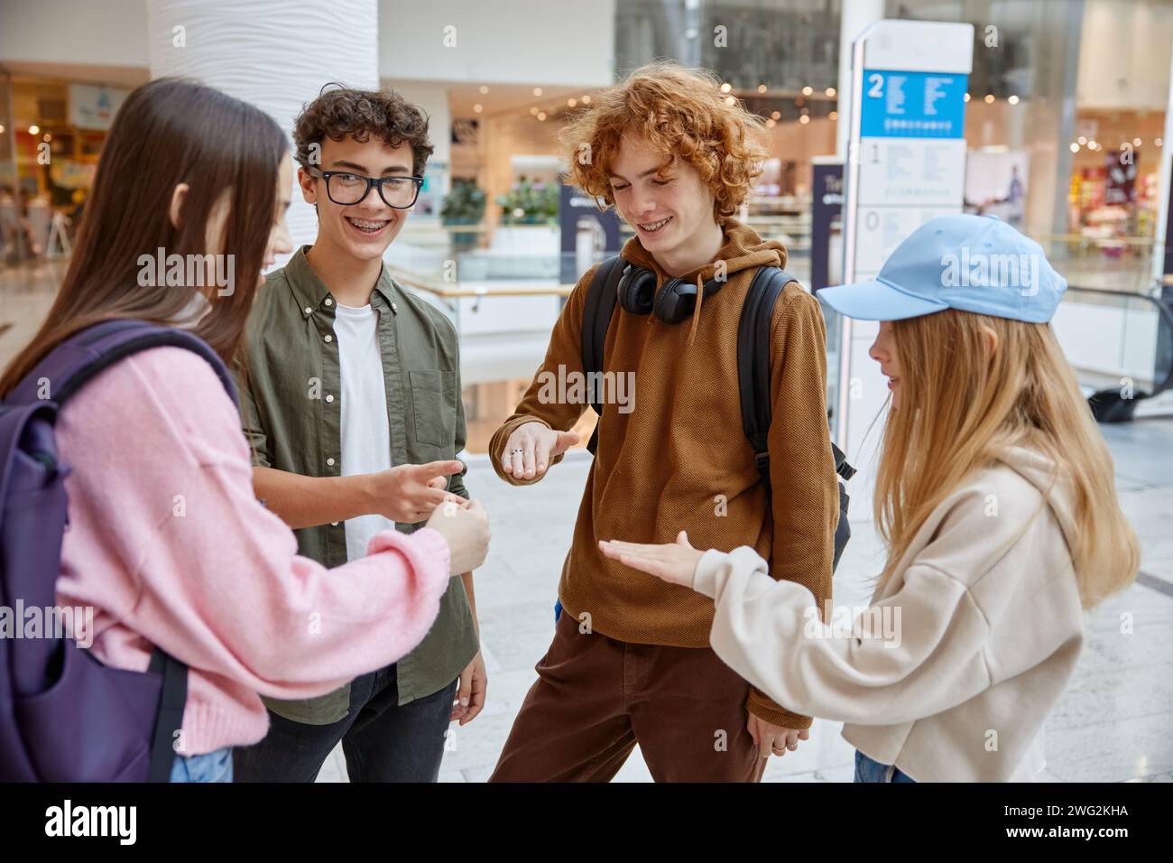 Teenagers friends playing rock-paper-scissors hand game at shopping ...