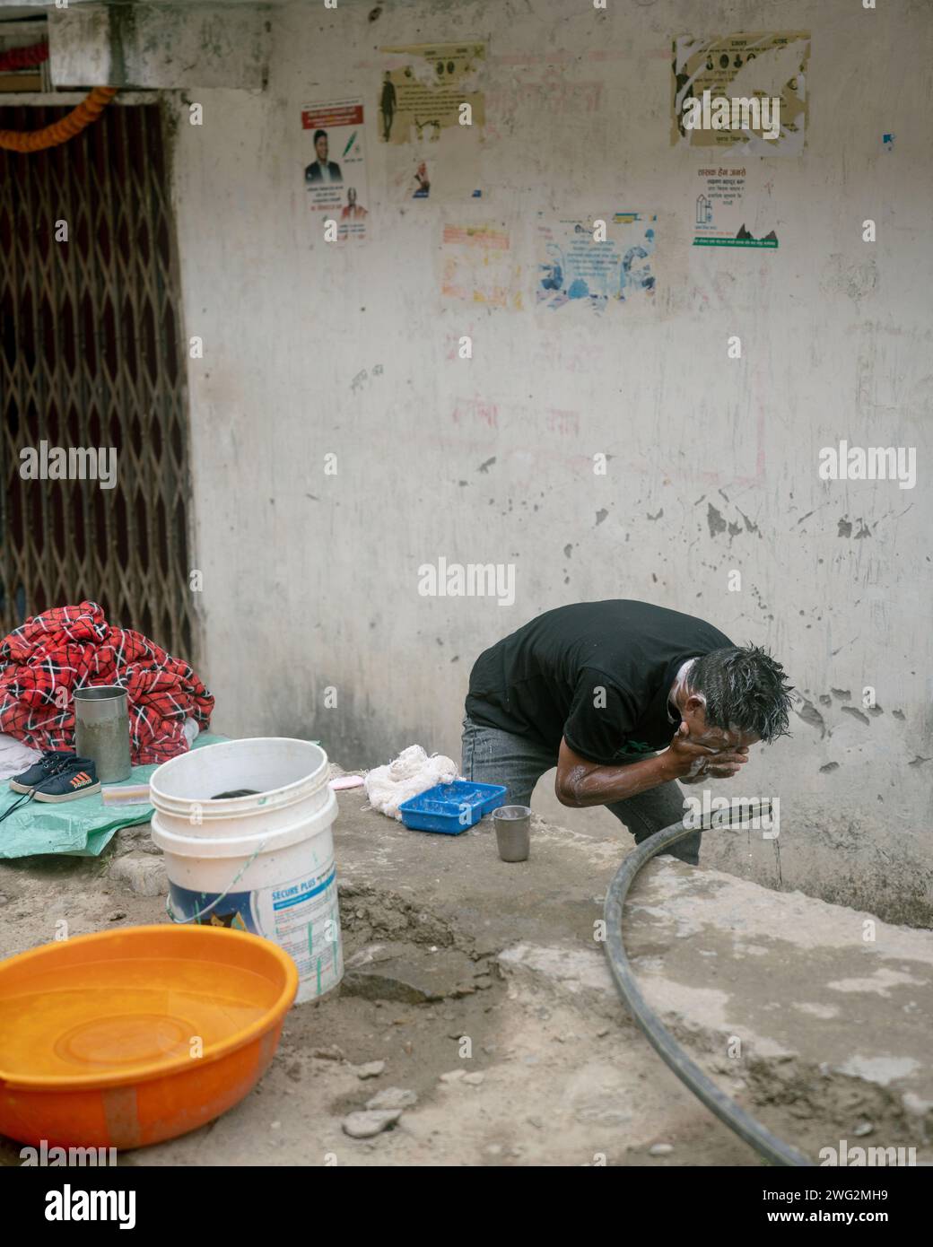 A Nepali Man Washes Himself At The Side Of The Road By A Plastic