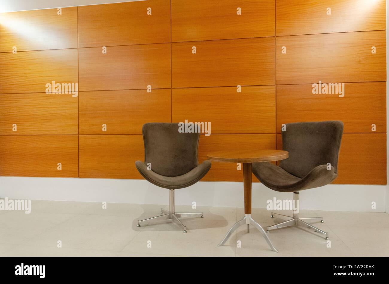 Two chairs and a table sit in a stylish office, against a backdrop of a ...