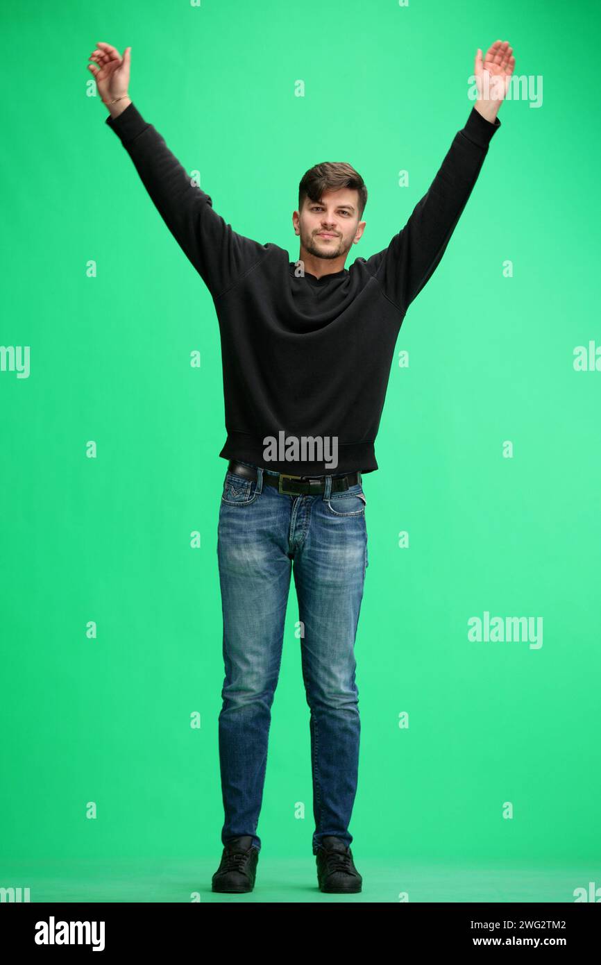 A man, full-length, on a green background, waving his arms Stock Photo ...