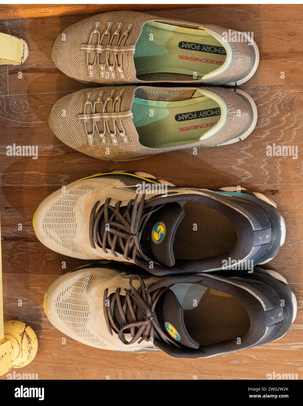 A man's pair of athletic shoes sits side by side with a pair of women's ...