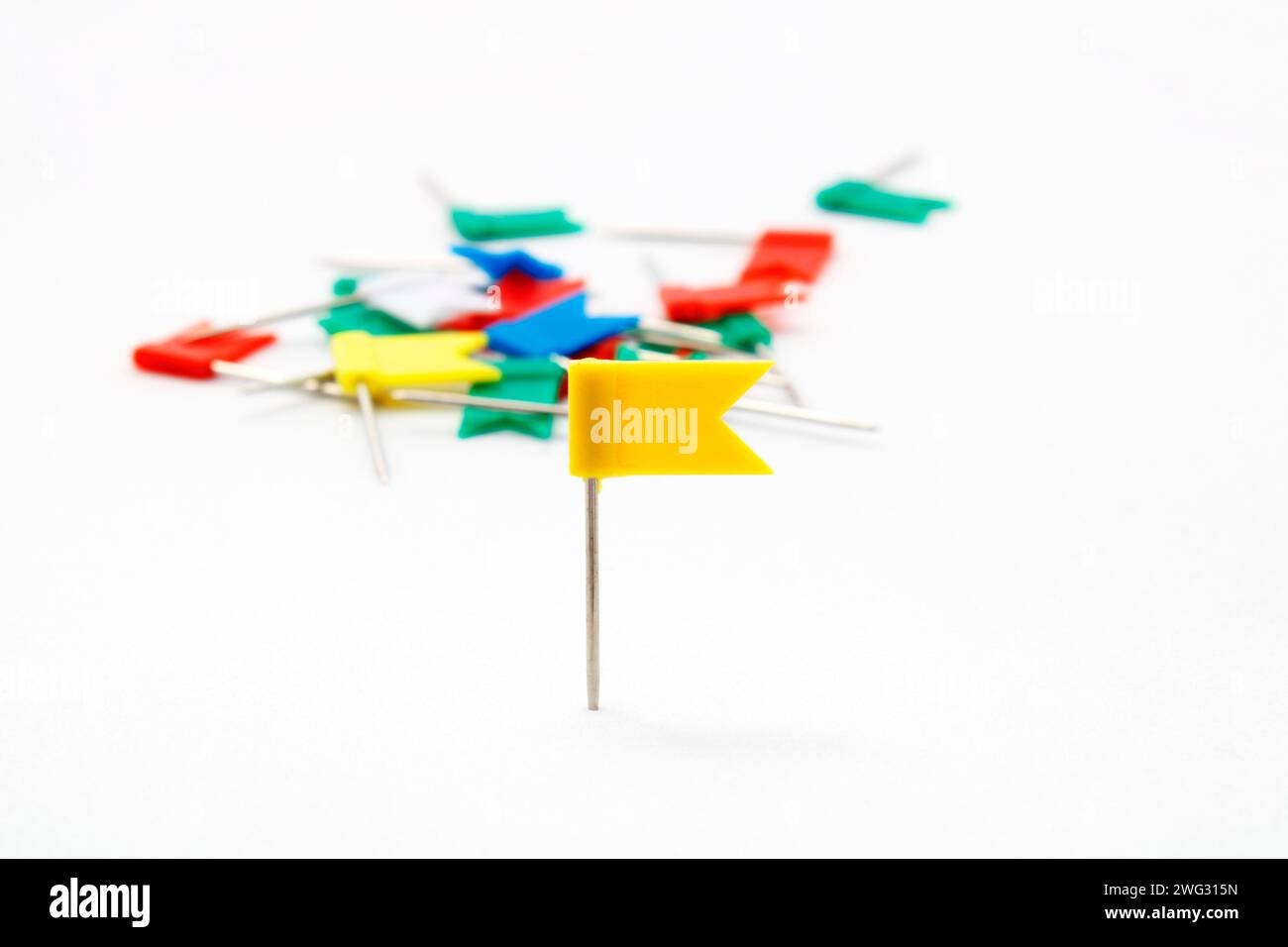 Yellow flag shaped thumbtack standing in front of other fallen ones of ...