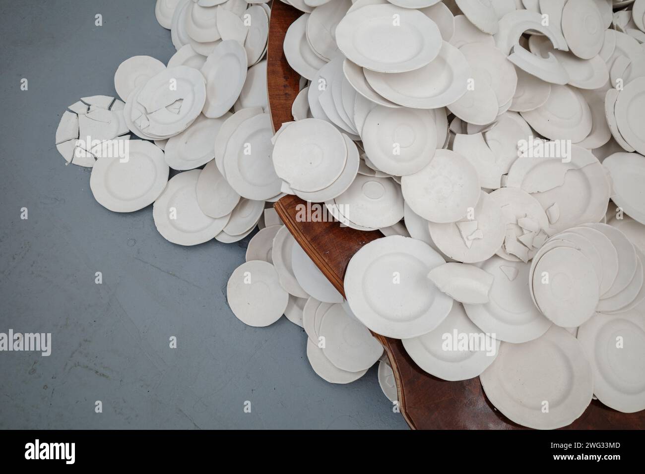 A pile of white, unfinished ceramic plates at various stages of the ...