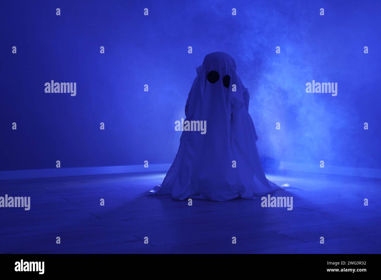 Creepy ghost. Woman covered with sheet in blue light Stock Photo - Alamy