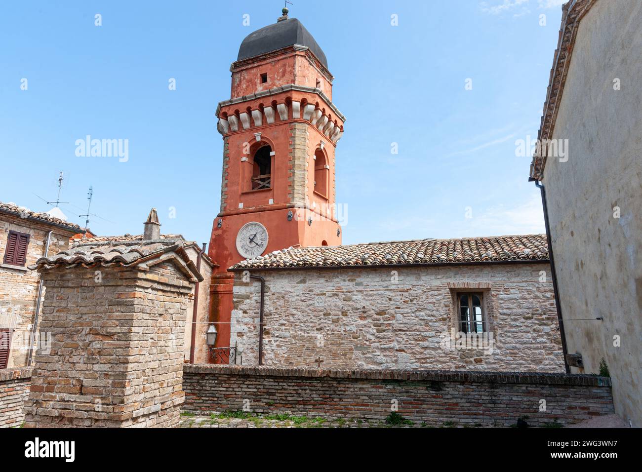 Orange colour medieval clock tower with lower stone buildings below in ...