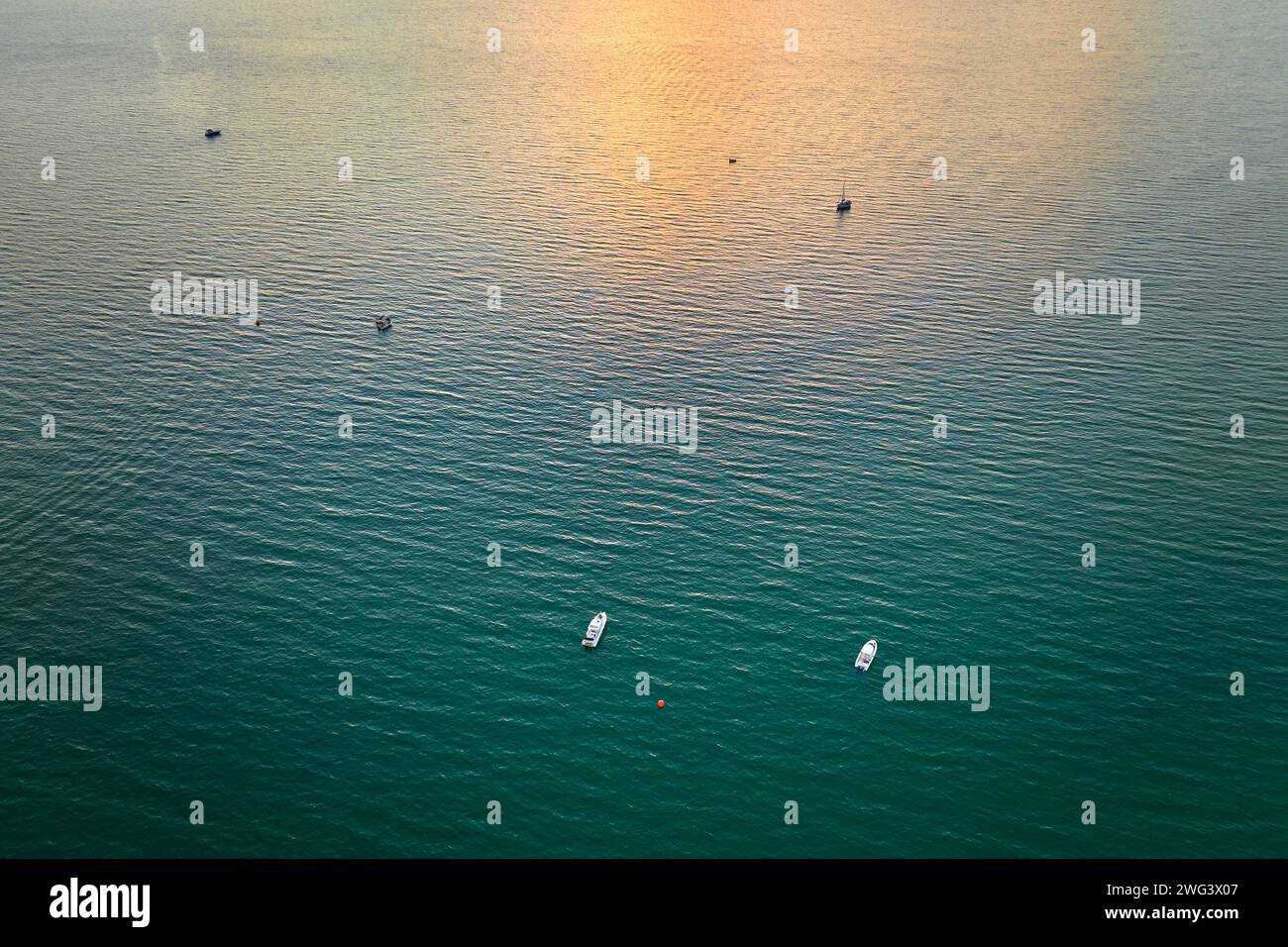 Aerial view of small yachts at sunset floating on sea waves with ripple ...