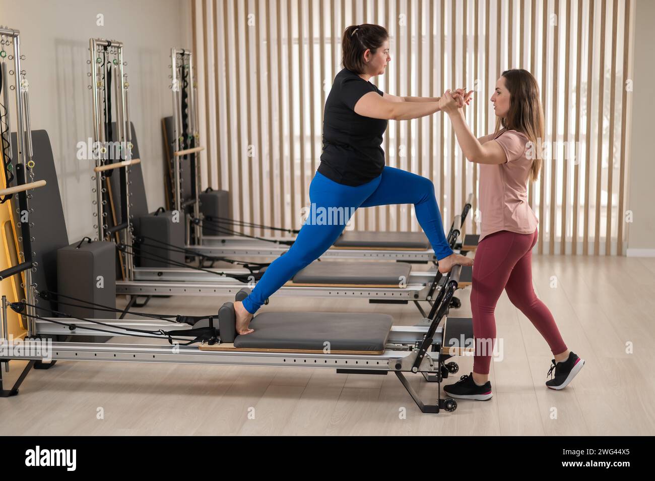 Overweight caucasian woman doing pilates exercises on reformer with ...