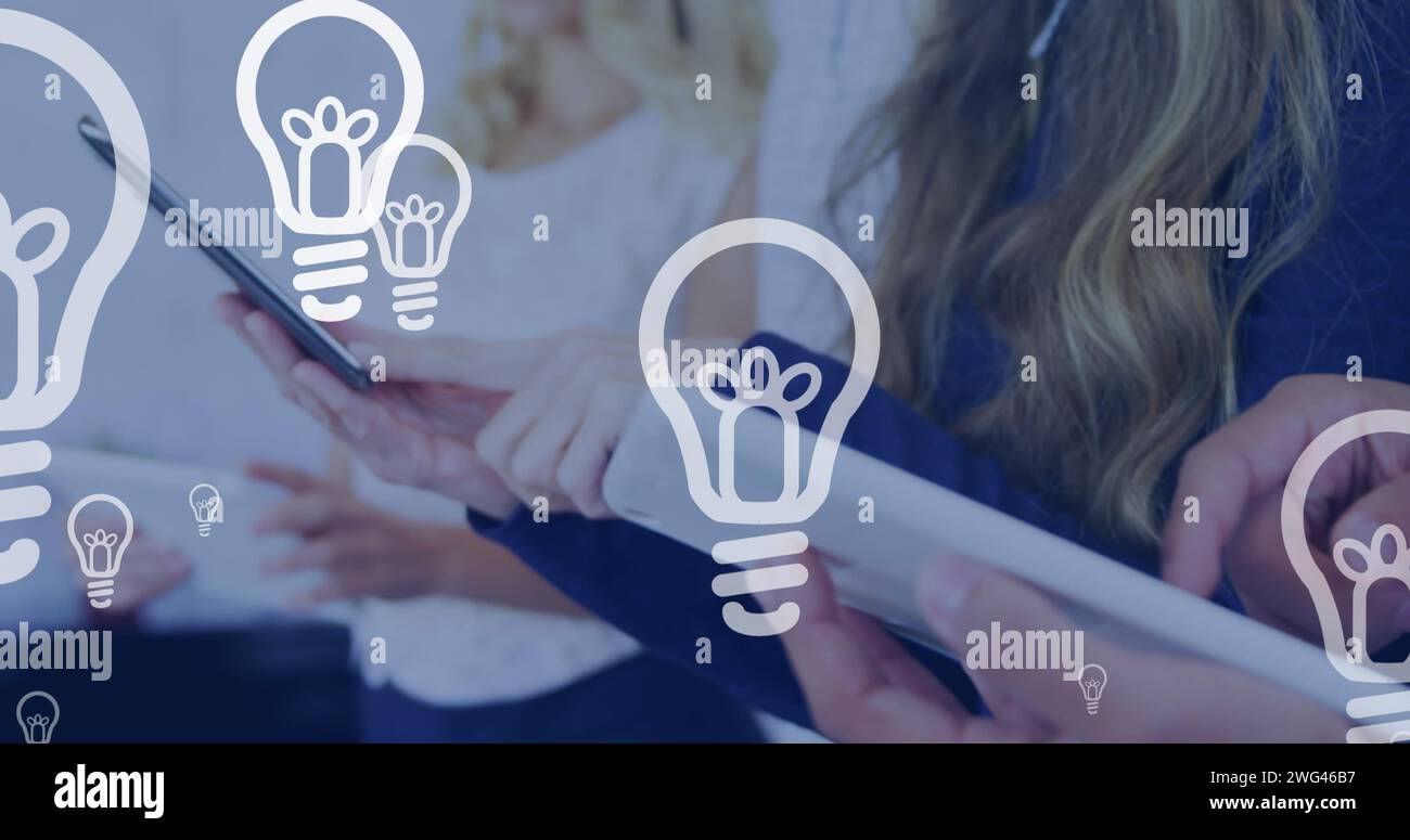 Light bulb icons floating against mid section of office colleagues ... Light bulb icons floating against mid section of office colleagues ...