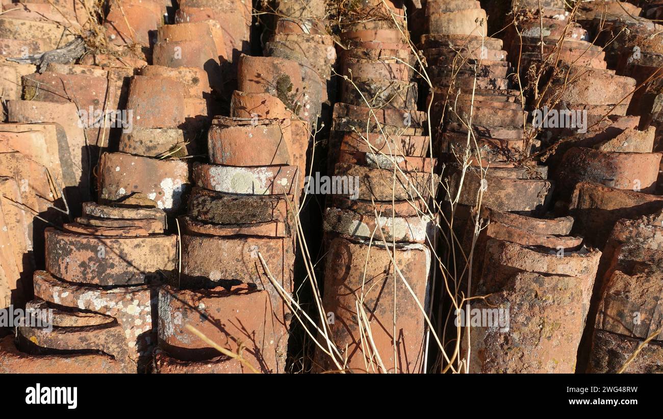 Hundreds of antique roof tiles piled in a row ready to be used for a ...