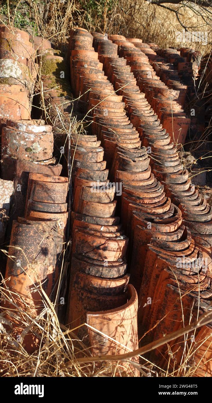 Hundreds of antique roof tiles piled in a row ready to be used for a ...