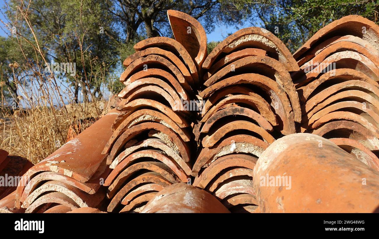 Hundreds of antique roof tiles piled in a row ready to be used for a ...