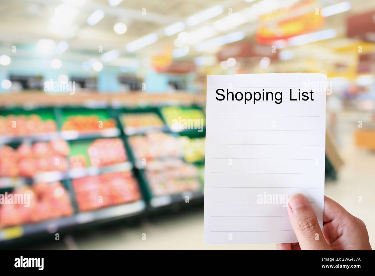 hand hold shopping list paper over fruits and vegetables on shelves in ...