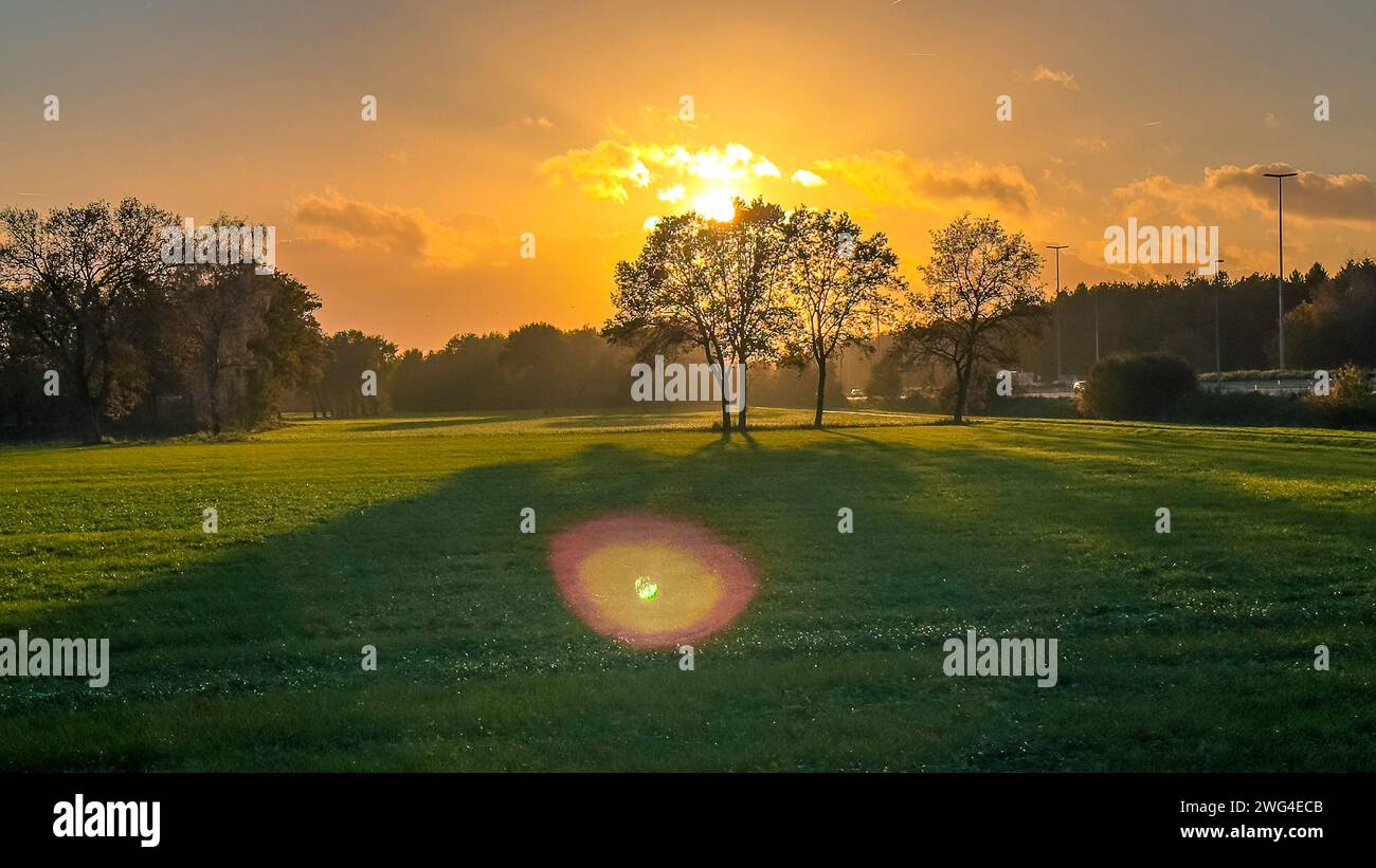 Sunset over a scenic landscape with clouds gathering above a field and ...