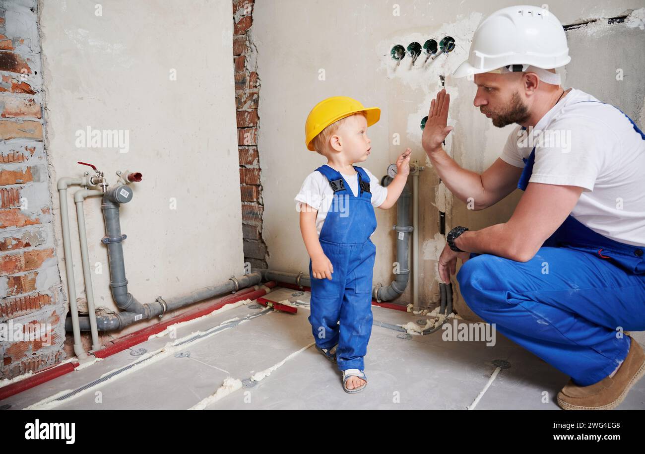 Male worker and little boy slapping hands giving high five in apartment ...