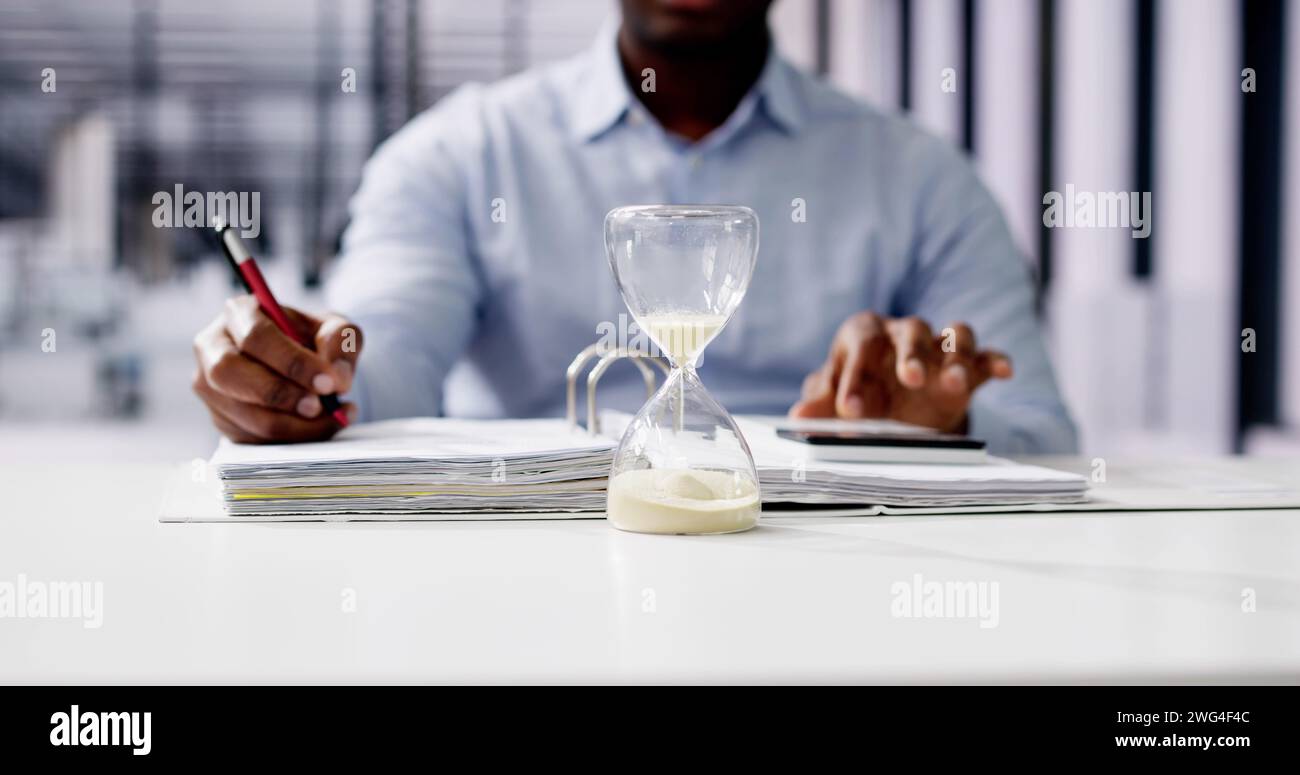 Hourglass And Time Crunch With Document In Office Stock Photo - Alamy