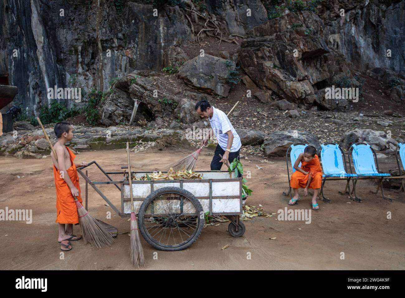 Young monks pick up leaves at the Wat Tham Pla Temple. Wat Tham Pla ...