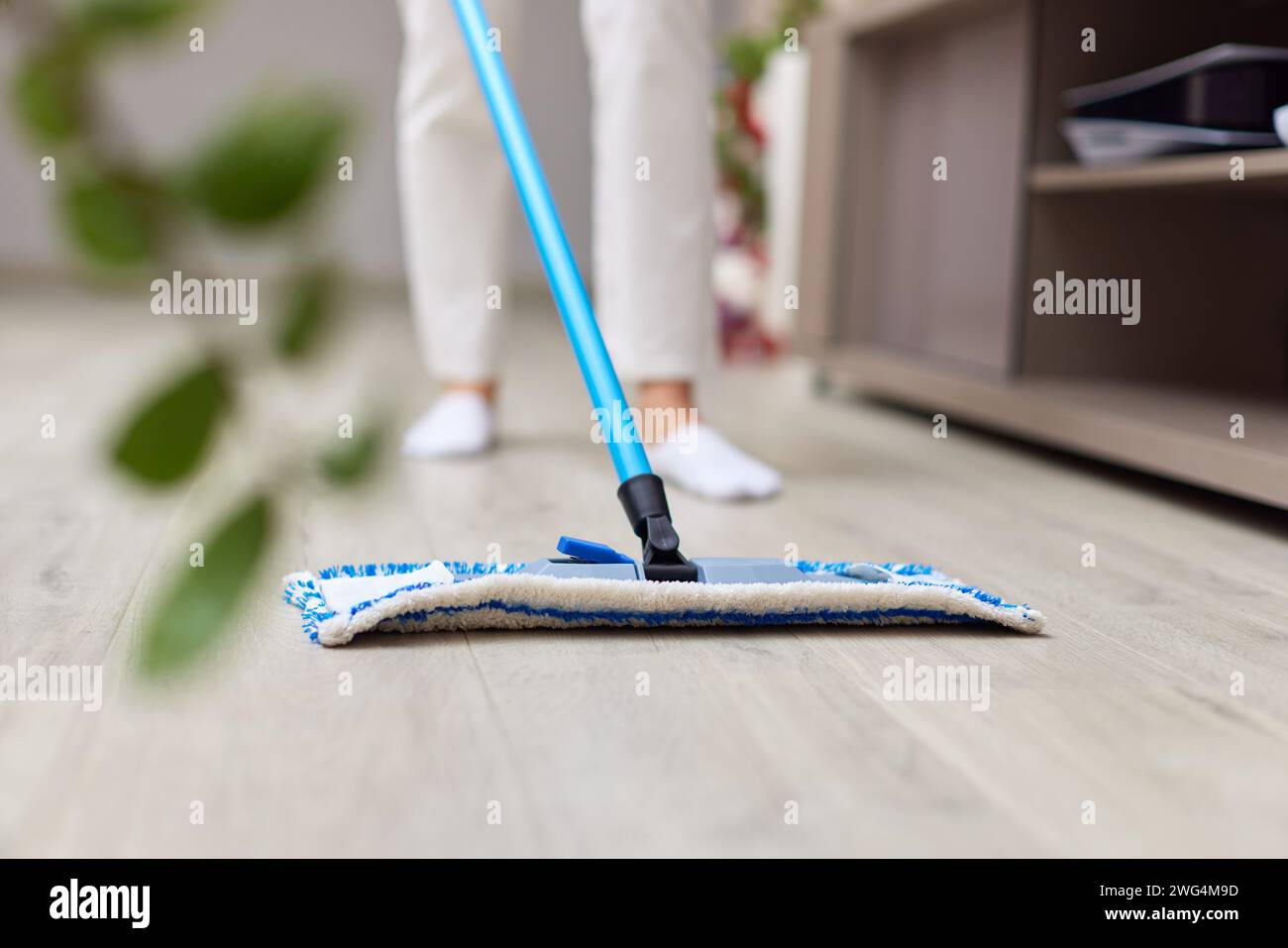 young woman cleaning and mopping floor at living room, daily ...