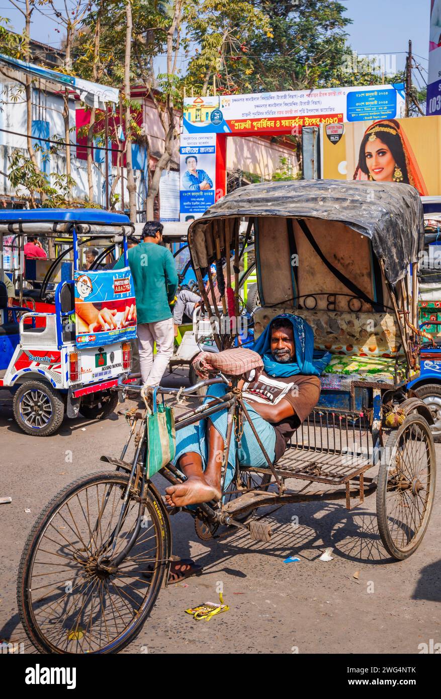 A local cycle rickshaw driver resting waiting for business in a street ...