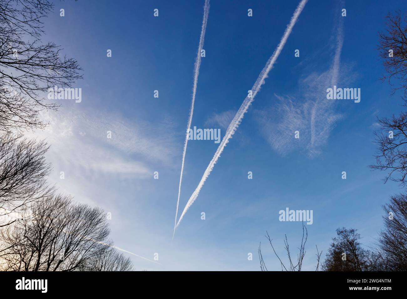 Converging vapour trails forming a V shape in a blue sky above ...