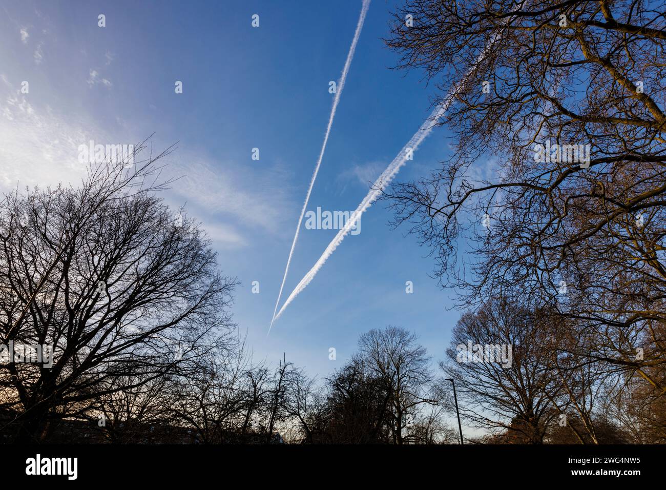 Converging vapour trails forming a V shape in a blue sky above ...