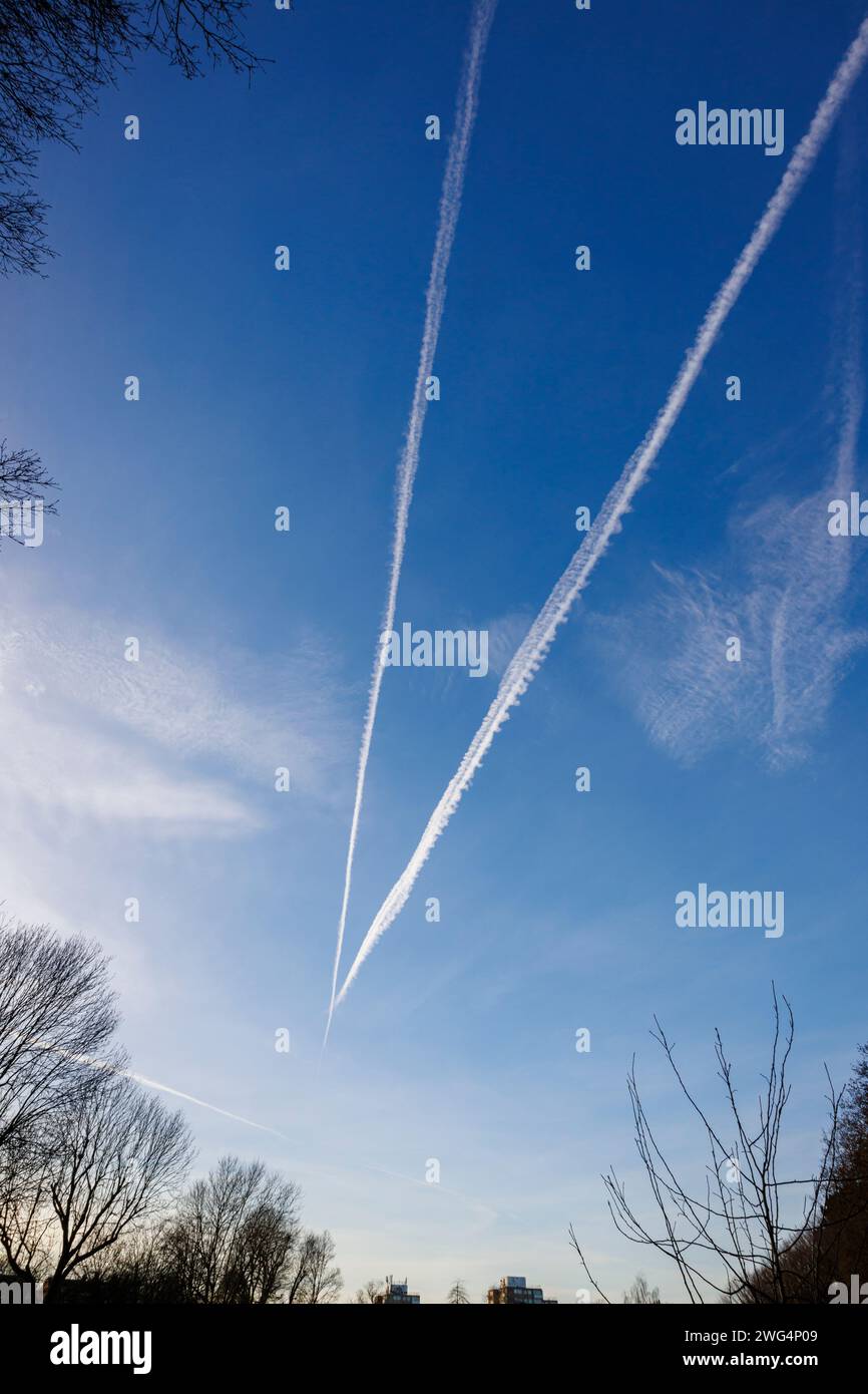 Converging vapour trails forming a V shape in a blue sky above ...