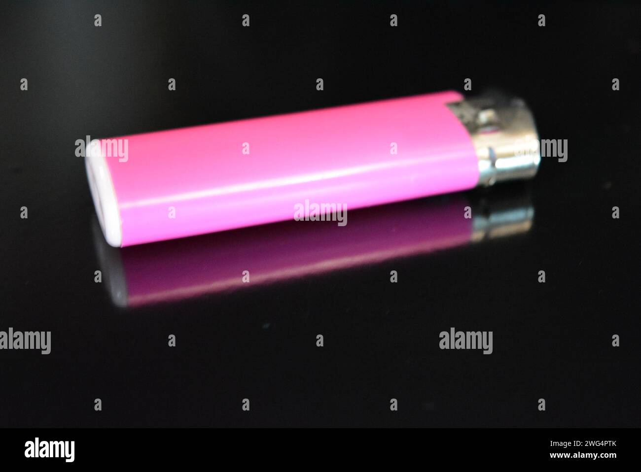 A pink plastic lighter lies on a glossy black surface Stock Photo - Alamy