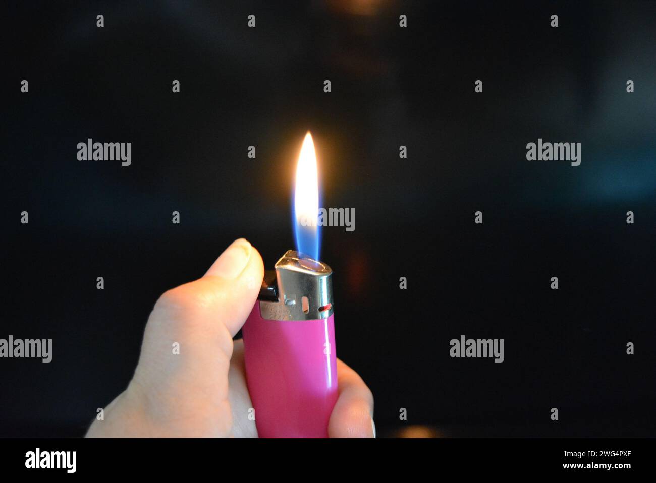 The fire and the included pink plastic lighter lie in a female hand on ...