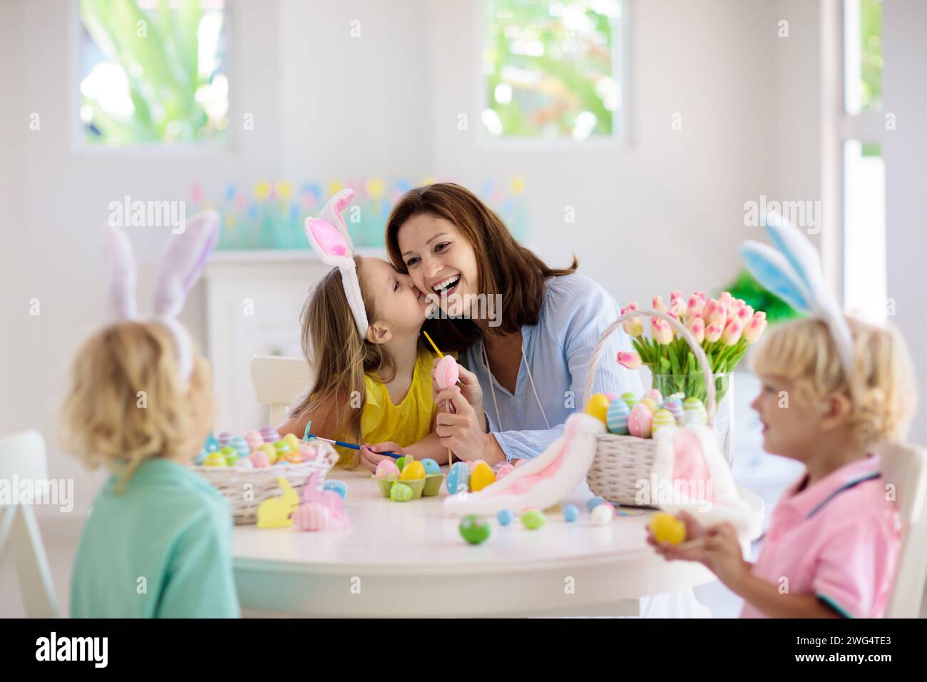Mother and kids color Easter eggs. Mom, little girl and boy with bunny ...