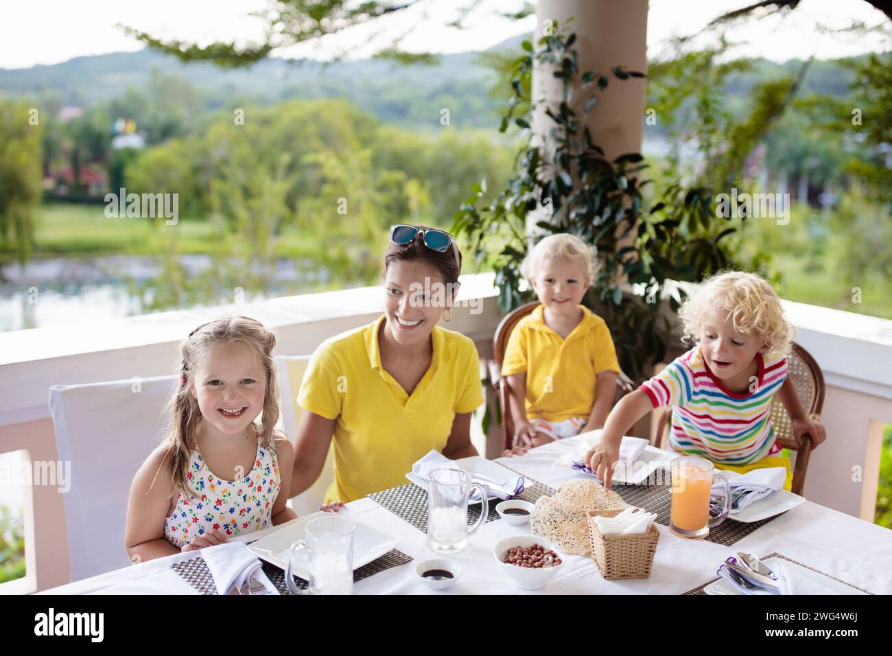 Family having dinner on outdoor patio. Mother and kids eating breakfast ...