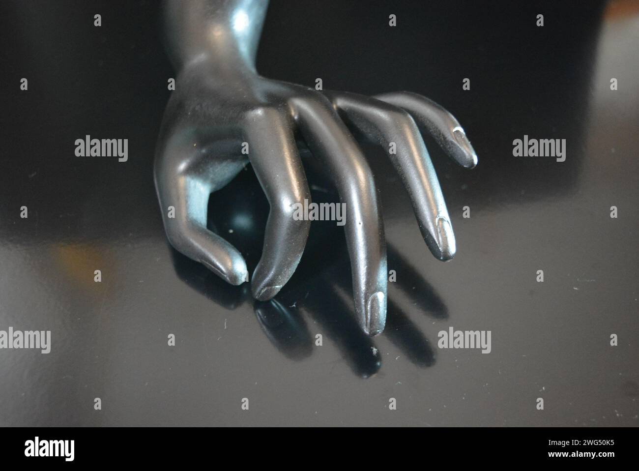 A matte black ceramic hand-shaped statuette is located on a matte black ...