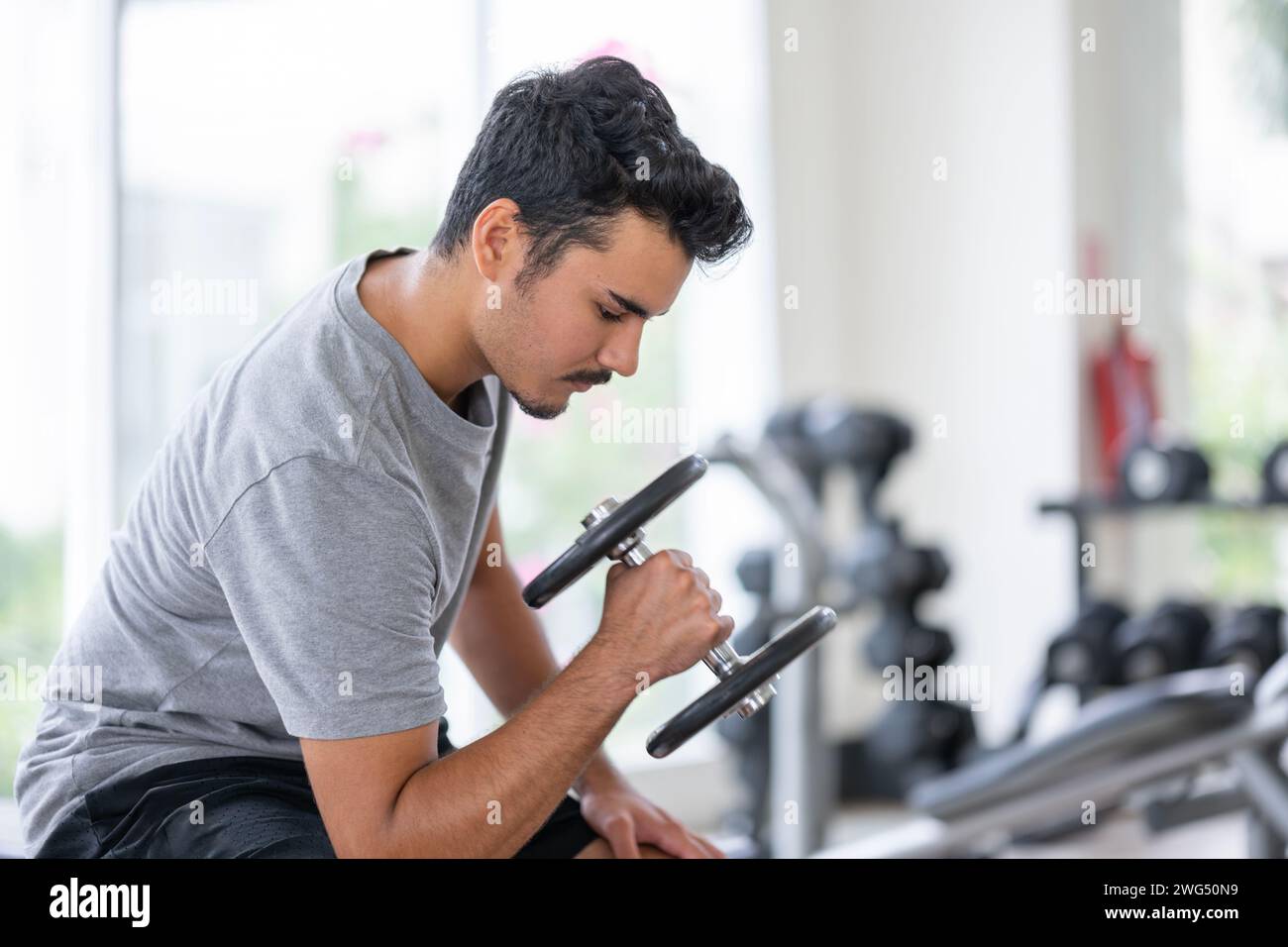 Focused Fitness Enthusiast Performing Bicep Curls With A Heavy Weight