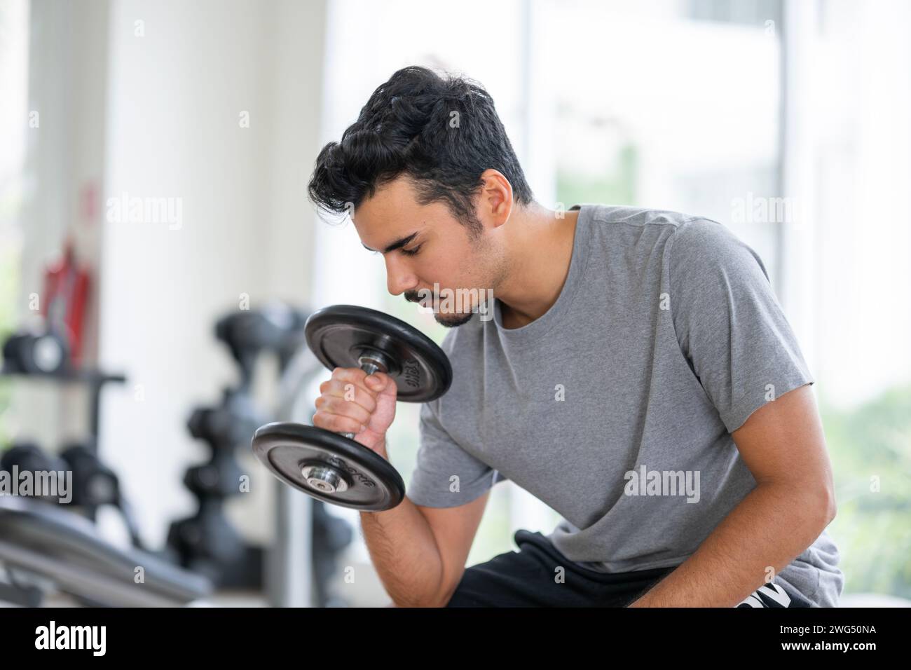 Dedicated athlete engaged in strength training with a single dumbbell ...