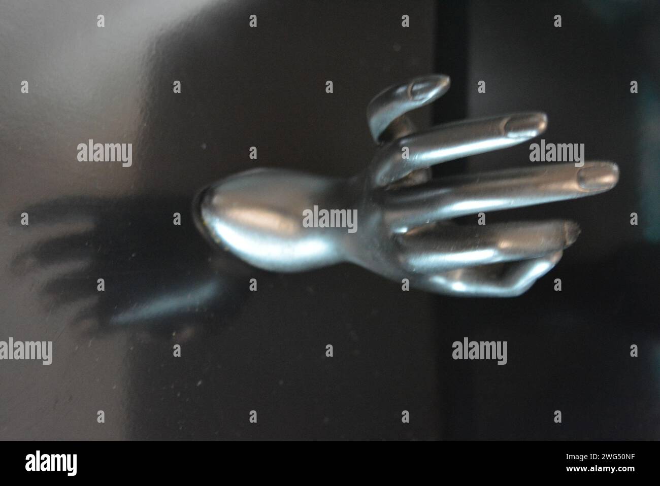 A matte black ceramic hand-shaped statuette is located on a matte black ...