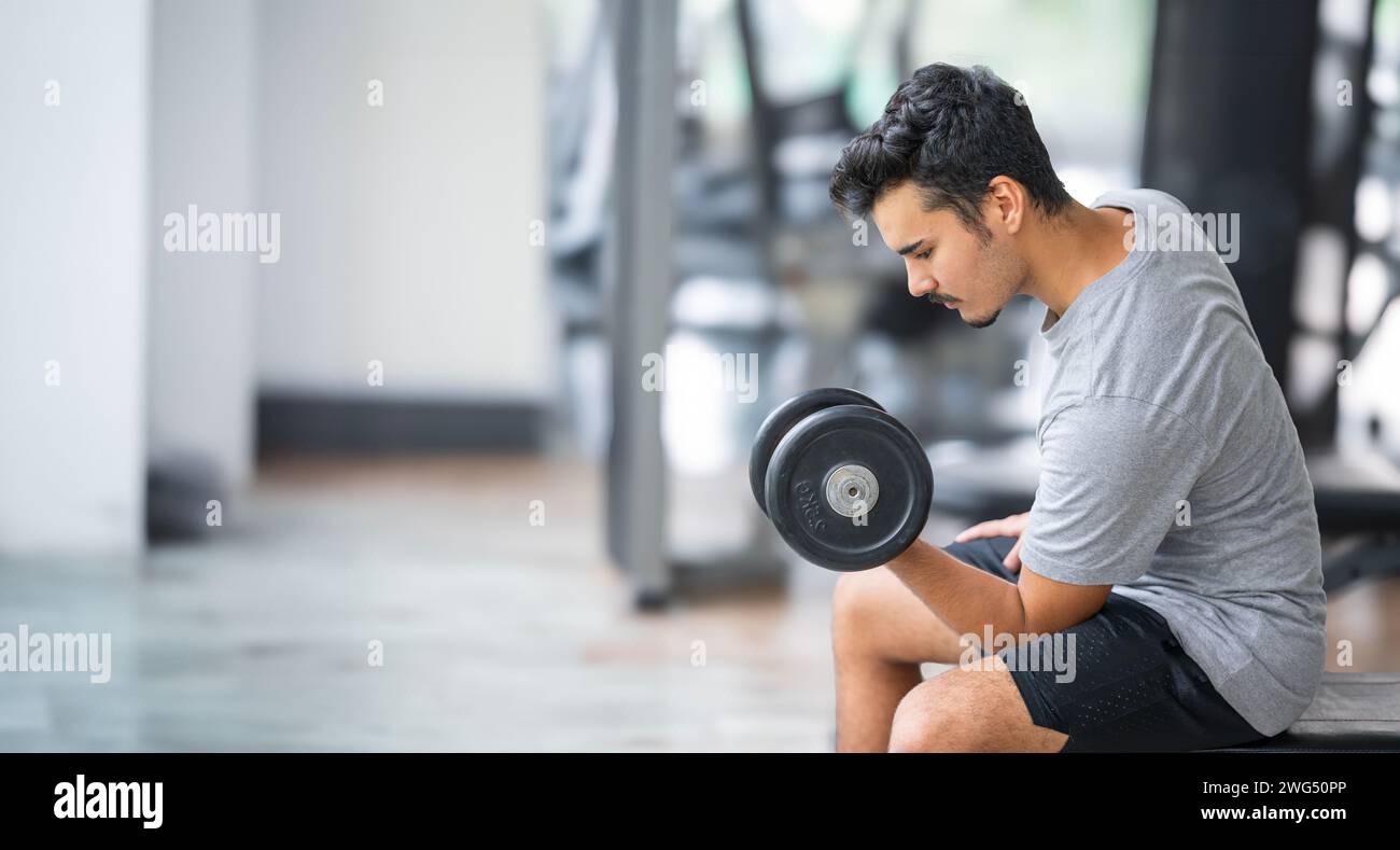 Serious gym-goer perfecting his form while lifting a black dumbbell ...