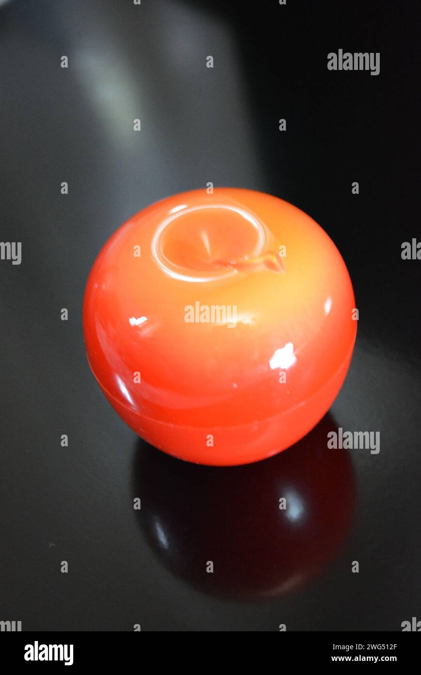 A bright red yellow plastic apple in which a cream of skin and face ...