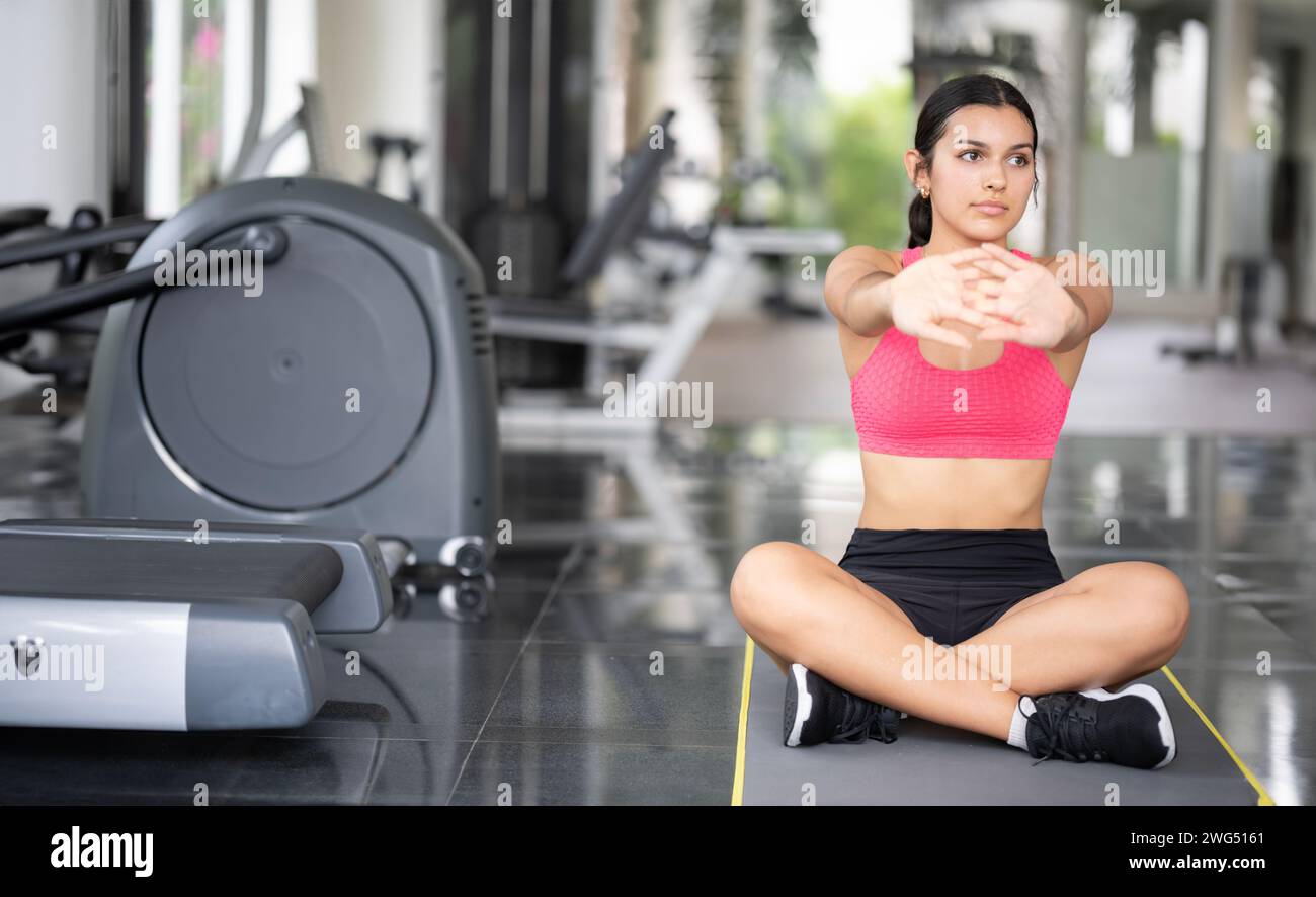 A young woman centers herself with a stretching routine in a spacious ...