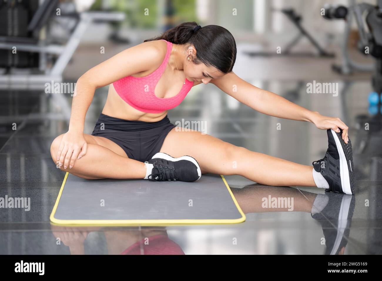 Fit woman doing stretching exercises on a yellow mat at a fitness center Stock Photo - Alamy