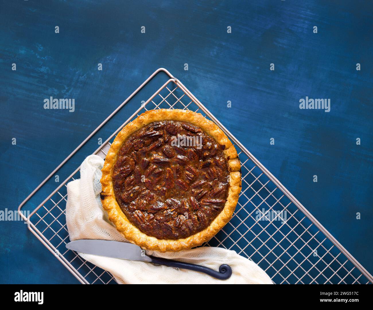 Overhead view of a small pecan pie a cooling rack with a gauze linen ...