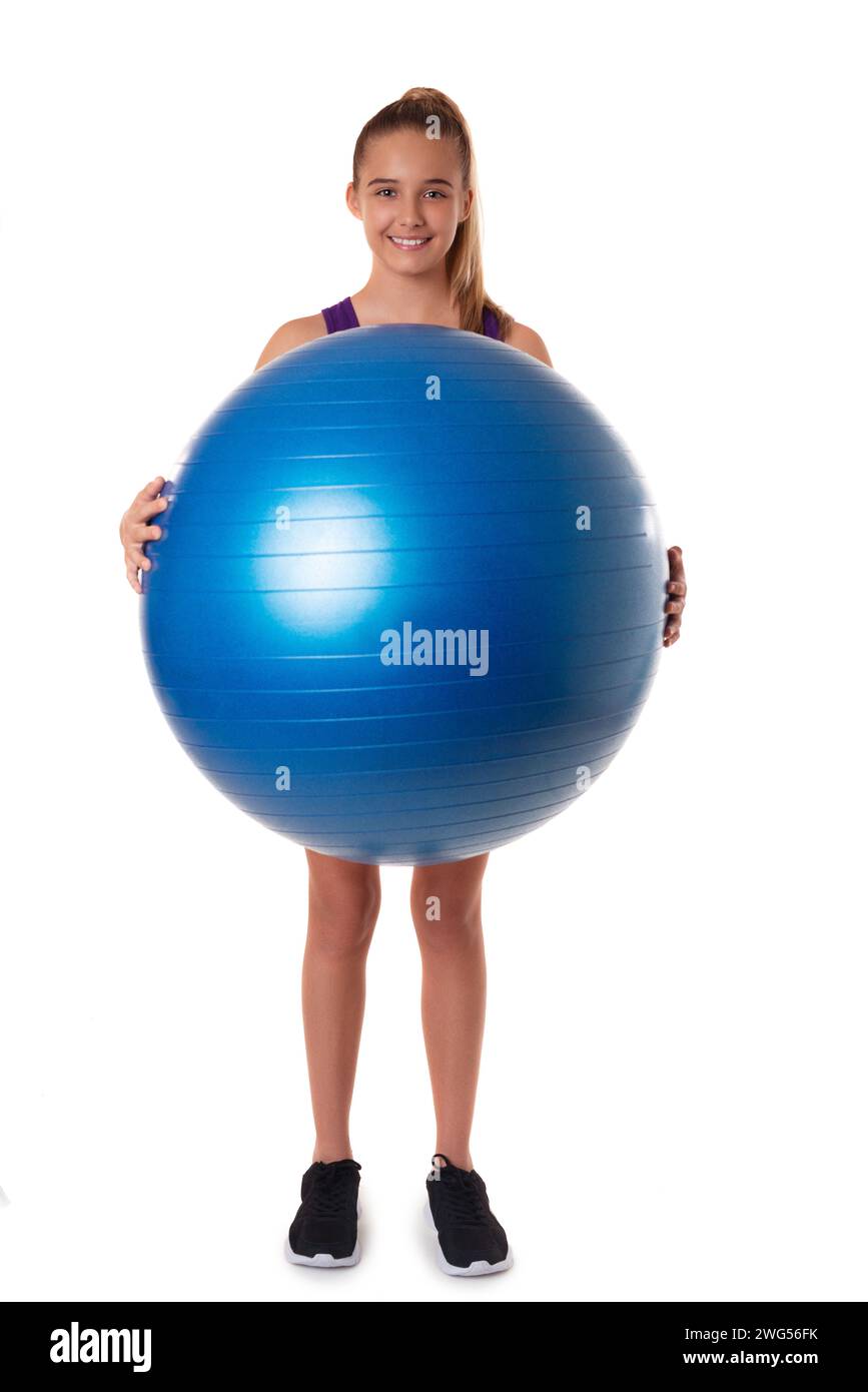 Slim and fit teen girl holding a swiss ball. Full length shot on white ...