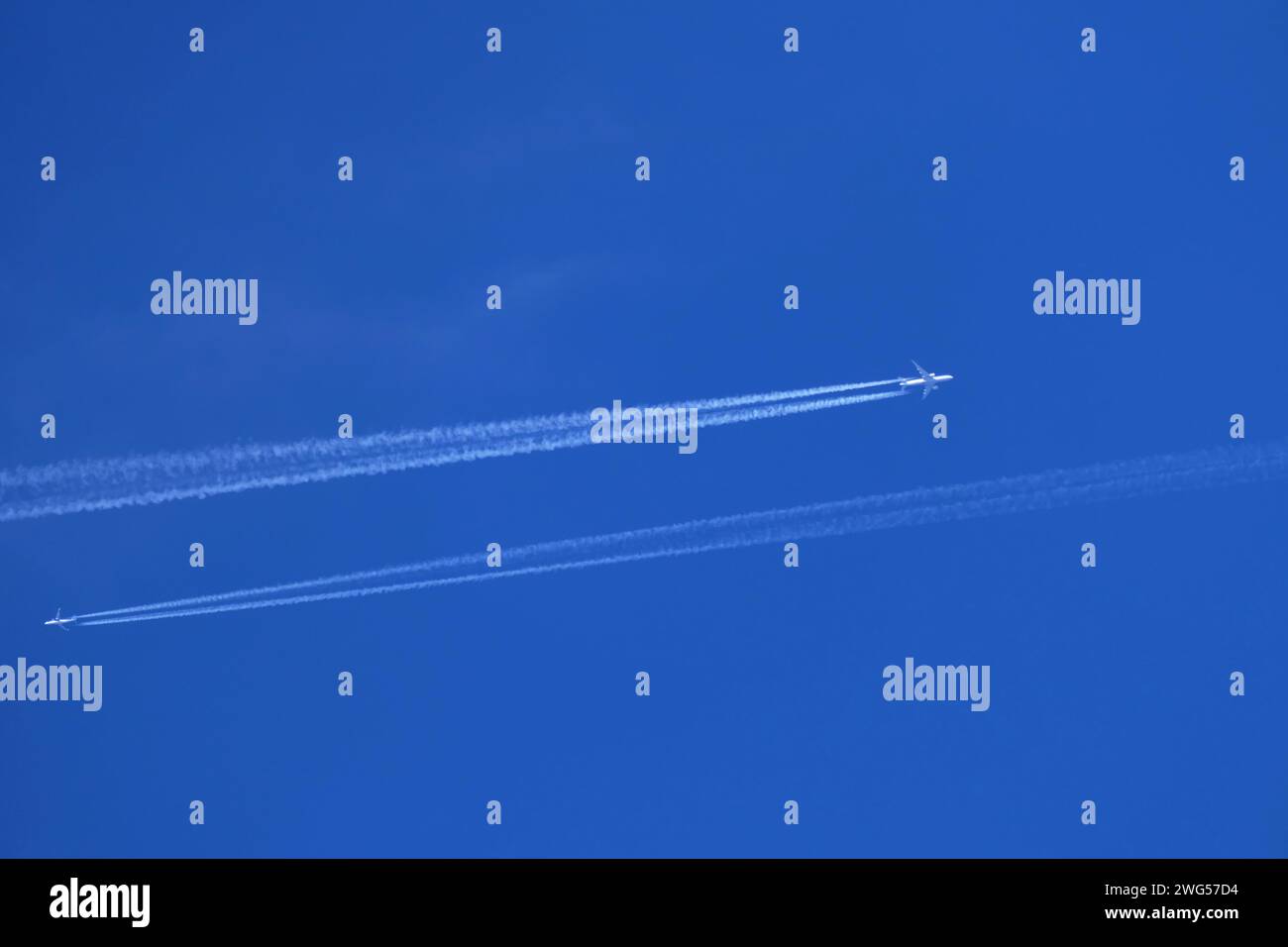 Two airplanes in the blue sky with contrails Stock Photo - Alamy
