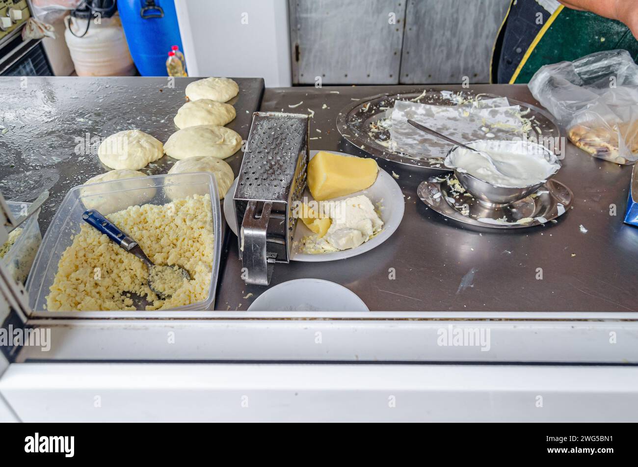 Street vendor stall preparing langos with grated cheese and sour cream ...