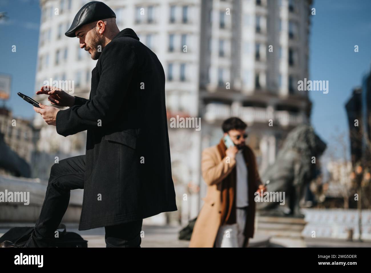 Two fashionable businessmen work remotely using smart phones in a ...