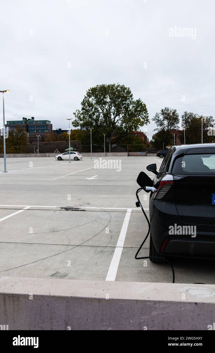 Black electric car charging at a parking lot Stock Photo - Alamy