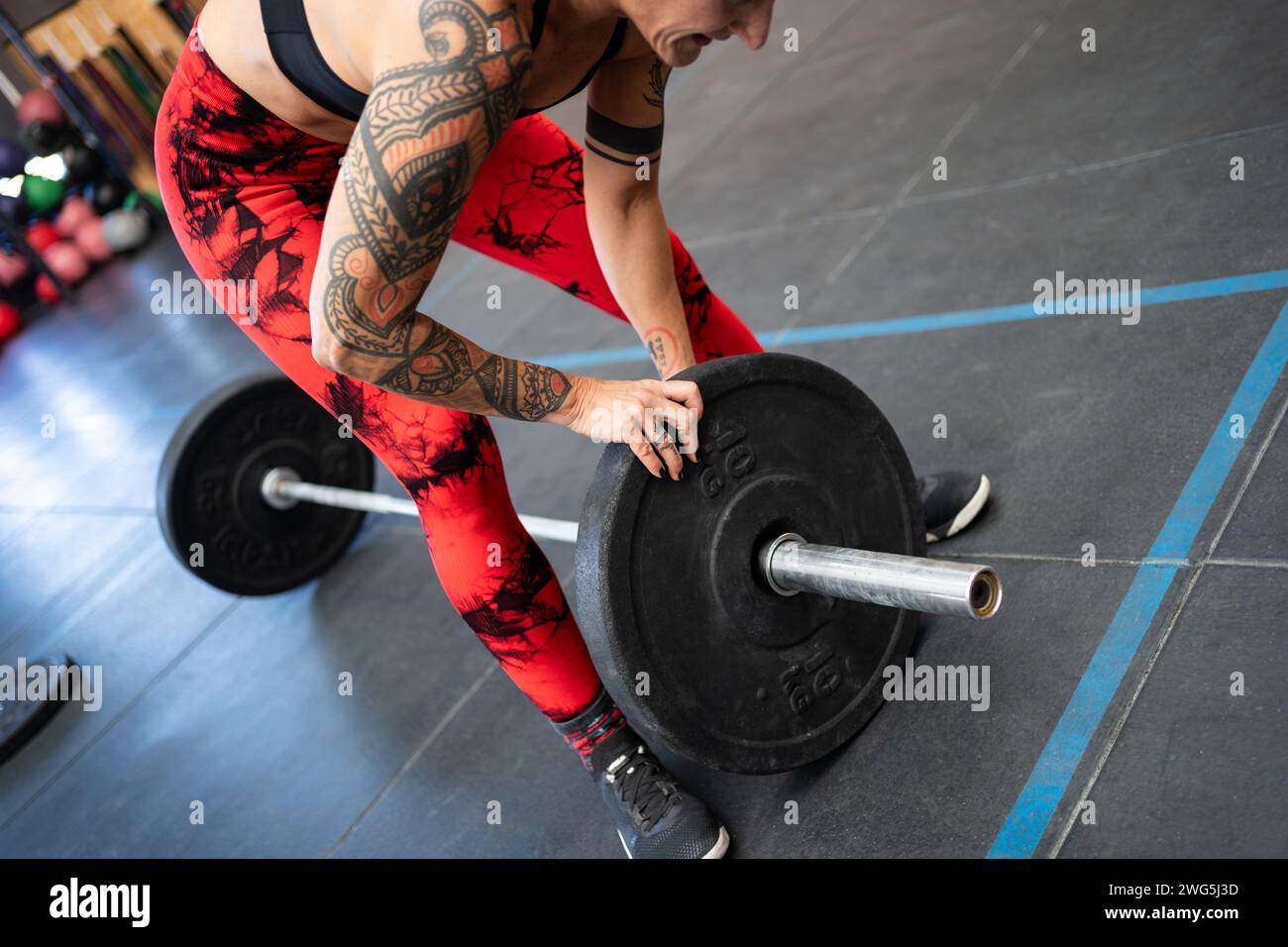 Woman adding weight to a bar for weightlifting Stock Photo - Alamy