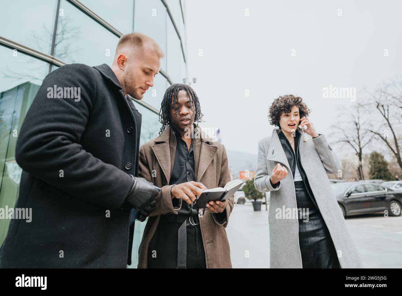 Three young, multiracial people engage in a business meeting outdoors ...