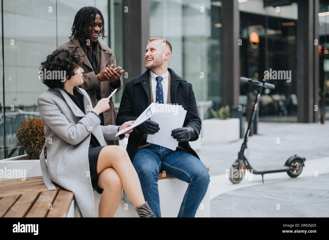Three multiracial business people happily engaging in a conversation ...