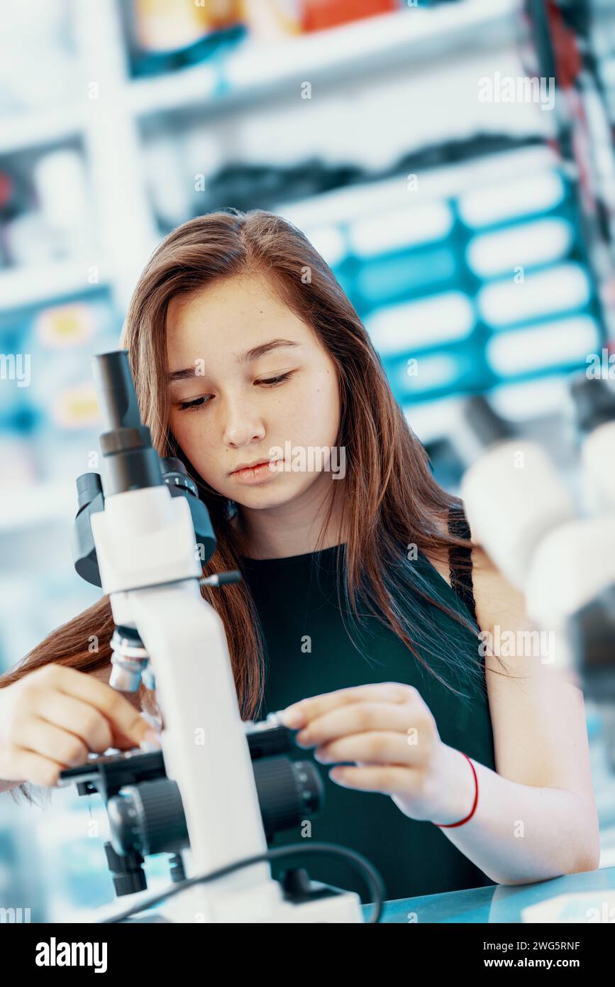 teenage girl in science class use microscope Stock Photo - Alamy